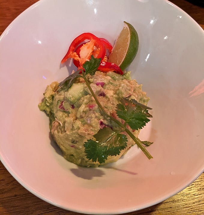 This guacamole is sculpted like edible art, garnished with cilantro and red pepper that pop against the creamy green canvas of perfectly ripened avocados.