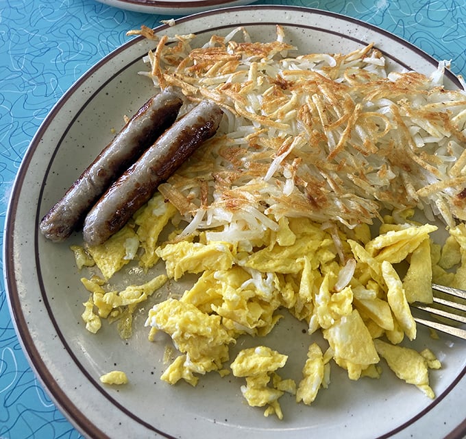 These aren't just hash browns – they're golden potato perfection with sausage links standing by like delicious sentries guarding your breakfast happiness.