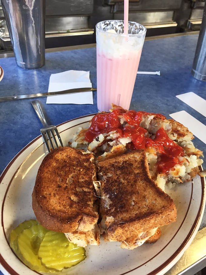 A grilled cheese sandwich and hash browns with ketchup sit beside a strawberry shake—the holy trinity of diner comfort that transcends generations.