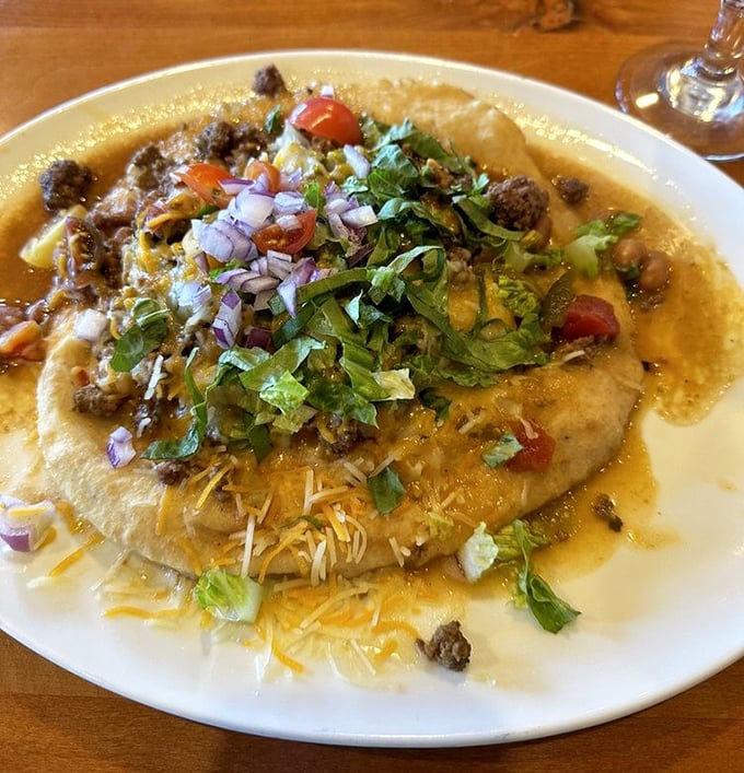 The Indian Taco isn't just food—it's edible architecture. A golden fry bread foundation supports layers of savory goodness topped with garden-fresh garnishes.