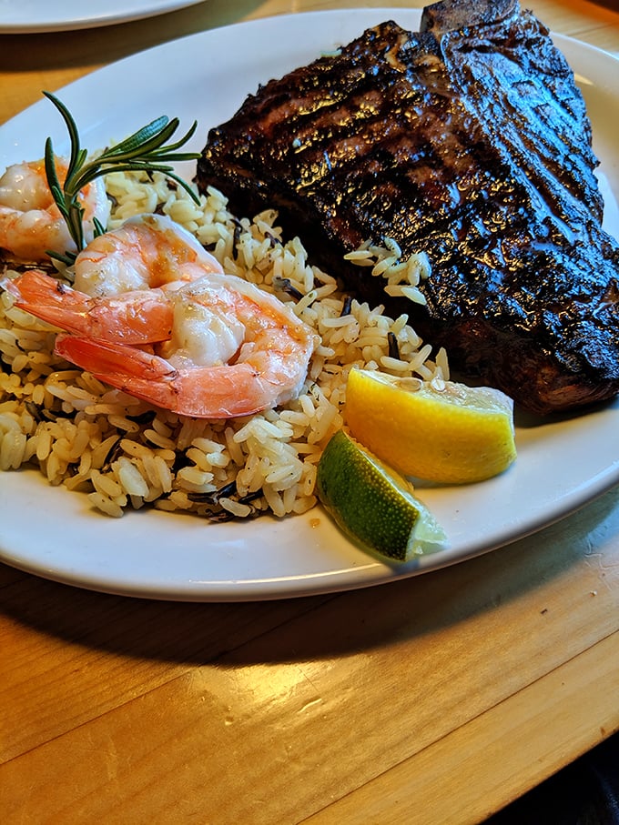 Surf meets turf in perfect harmony—charred steak with plump shrimp nestled on a bed of rice. The citrus wedges aren't decorative; they're essential.