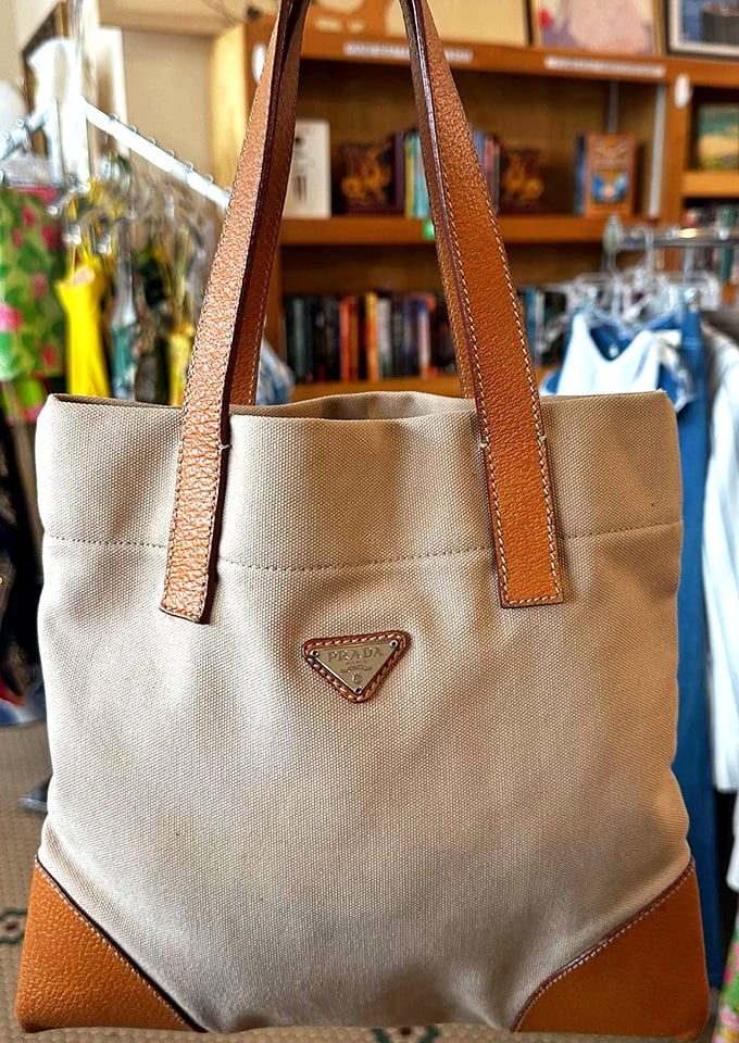 A Prada canvas tote with leather trim waits patiently for its second act—proof that luxury labels regularly make surprise appearances among the racks.