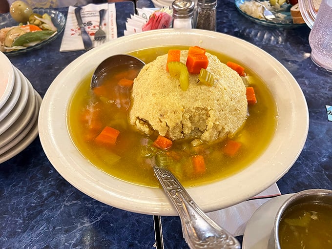 The matzo ball floats like a golden planet in a galaxy of savory broth – Jewish penicillin elevated to an art form.