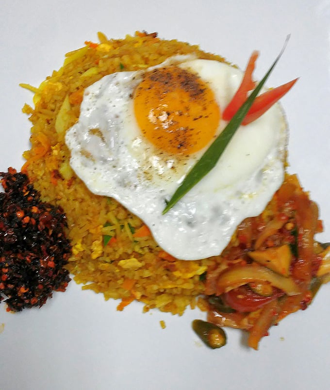 Yellow rice crowned with a perfectly fried egg—the breakfast of champions meets dinner of kings in this colorful plate of pure comfort.