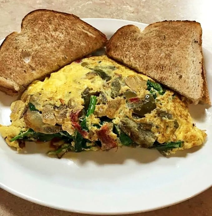 An omelet that's practically a geological expedition of flavors – layers of vegetables, cheese, and meat that would make any breakfast enthusiast weep with joy.