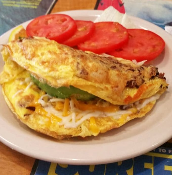 An omelet that doesn't hold back—stuffed with more fillings than my suitcase on vacation. Those tomato slices add the perfect fresh note.
