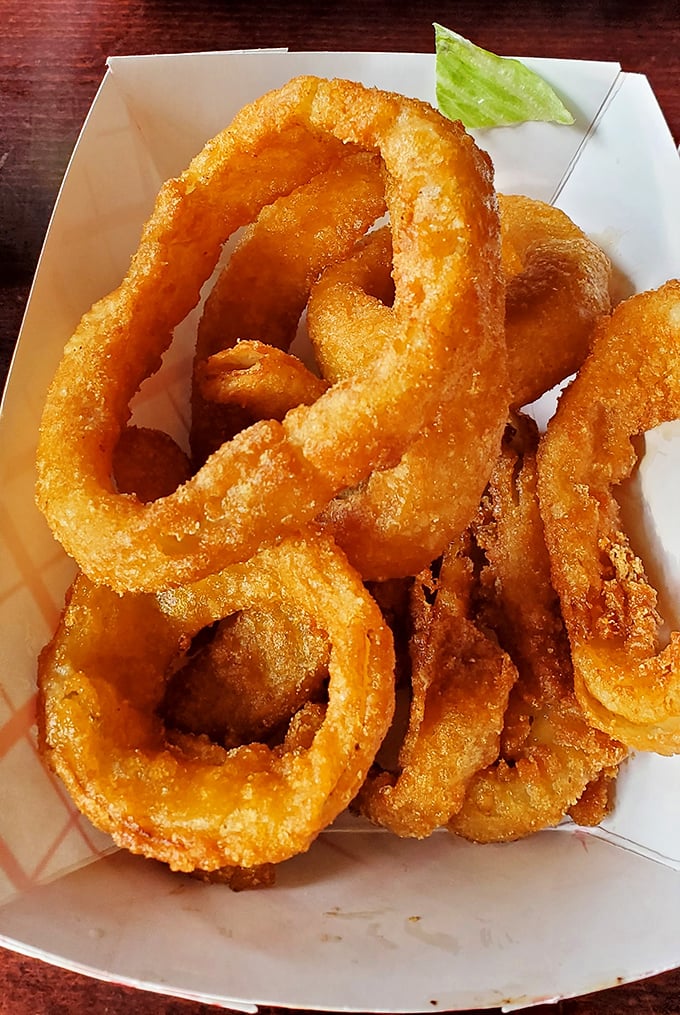 Golden onion rings stacked like delicious life preservers – crispy, substantial, and guaranteed to disappear from the table faster than you can say "just one more."