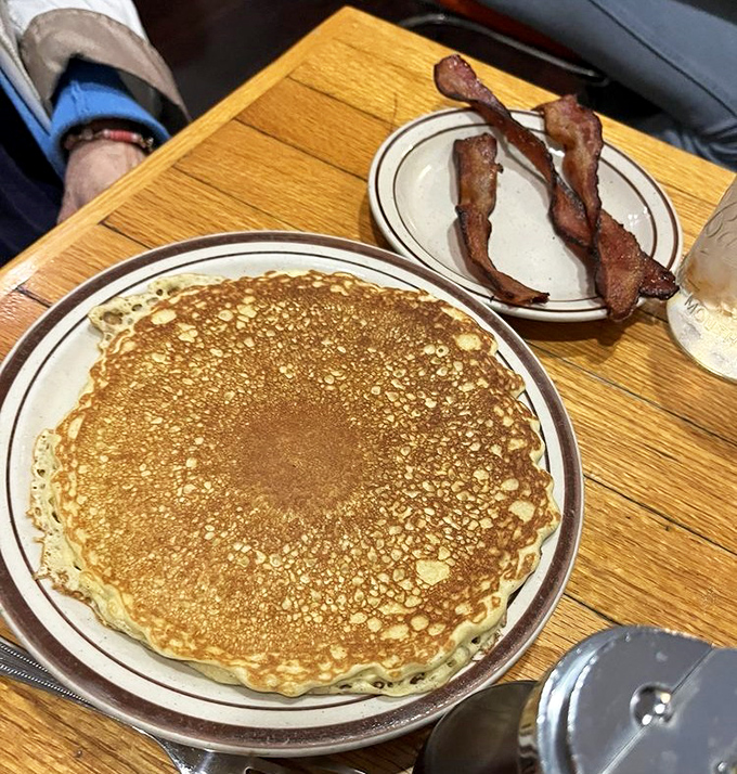 The perfect pancake doesn't exi— Oh wait, there it is, golden as a Midwest sunset, with bacon standing guard against healthy eating intentions.