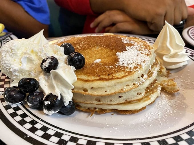 Pancakes stacked high with whipped cream and blueberries—because sometimes breakfast should look like it's celebrating something, even if that something is just Tuesday.