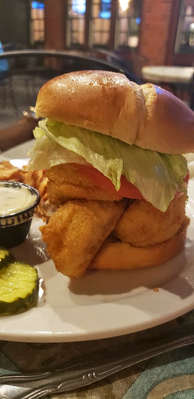 This perch sandwich isn't just food—it's architecture. Golden-battered fish stacked high with fresh toppings on a pillowy bun.