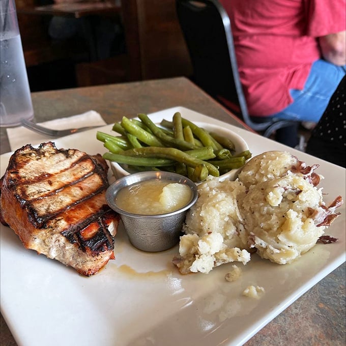 A perfectly grilled pork chop with green beans and loaded mashed potatoes—proof that simple food done right is culinary poetry.