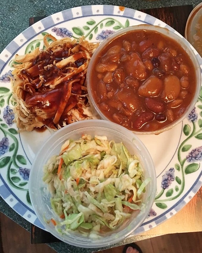 A plate that tells a story of patience—pulled chicken, beans, and slaw creating the holy trinity of barbecue satisfaction.