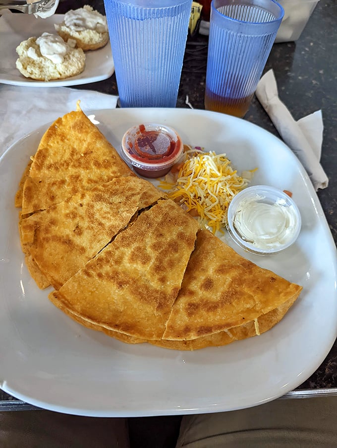This quesadilla isn't playing games—golden-crisp tortilla, melty cheese, and those little cups of sour cream and salsa standing by like loyal sidekicks.