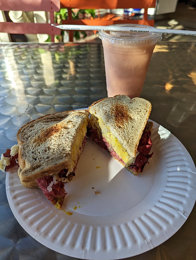 The Reuben, mid-bite—that magical moment when pastrami, melted cheese, and bread achieve perfect harmony on a paper plate.