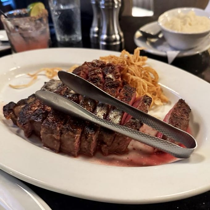 A ribeye sliced to reveal its perfect medium-rare interior – the kind of steak that makes conversation pause mid-sentence while everyone at the table stares in awe.