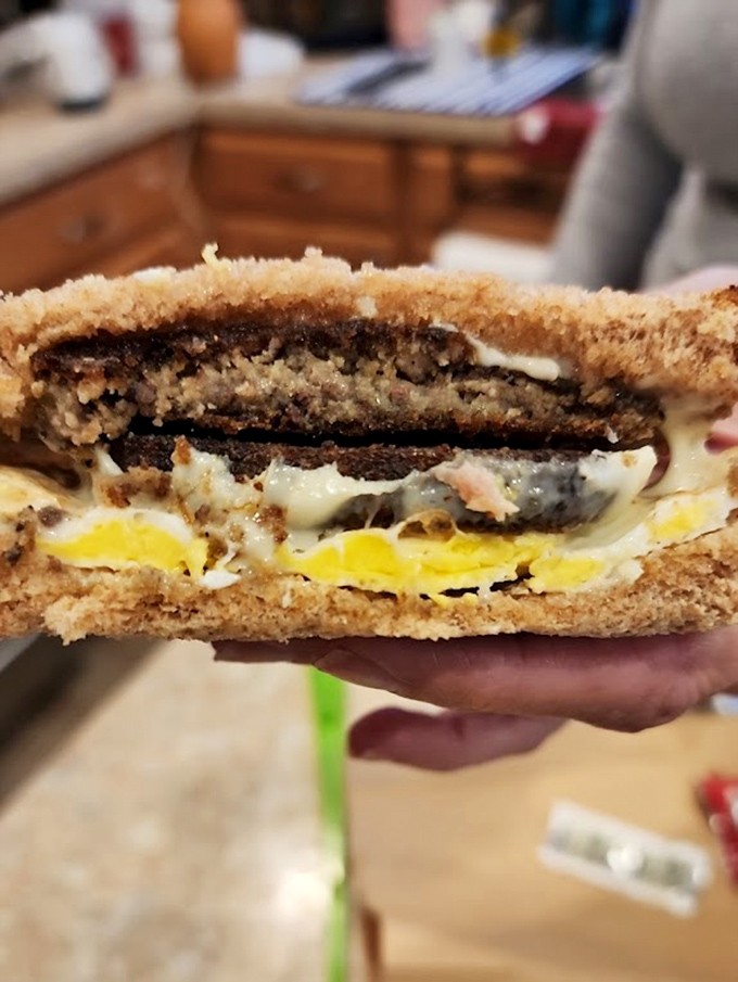 Layer upon layer of breakfast brilliance—scrapple, egg, and cheese creating a sandwich architecture that would make Frank Lloyd Wright jealous.