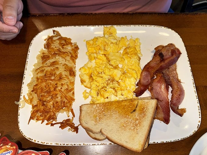 The holy trinity of breakfast—crispy hash browns, fluffy scrambled eggs, and bacon—assembled with the precision of a master craftsman.