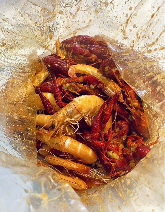 A clear plastic bag reveals a treasure trove of crawfish and shrimp, swimming in spiced sauce – seafood boils don't get more authentic than this.
