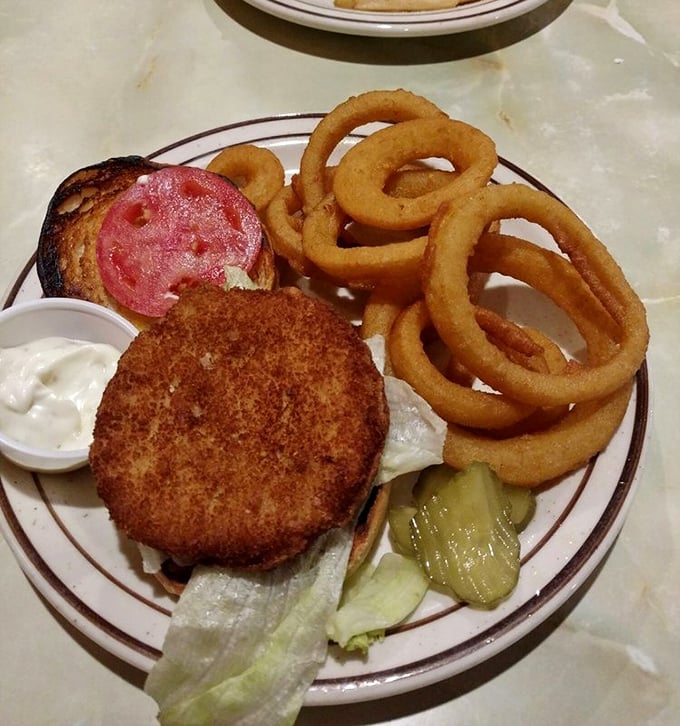 This isn't just a burger—it's a masterclass in diner engineering with golden-brown breading, crisp lettuce, and onion rings that demand attention.