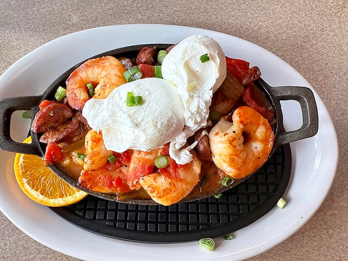 Poached eggs crown this skillet of shrimp and savory goodness like royal jewels. The orange slice isn't garnish—it's necessary brightness.