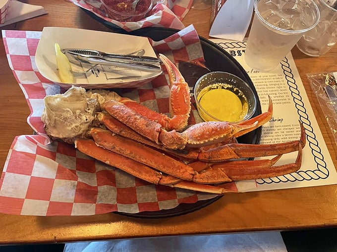 Snow crab legs sprawled across red-checkered paper – nature's puzzle that rewards patience with sweet, tender meat.