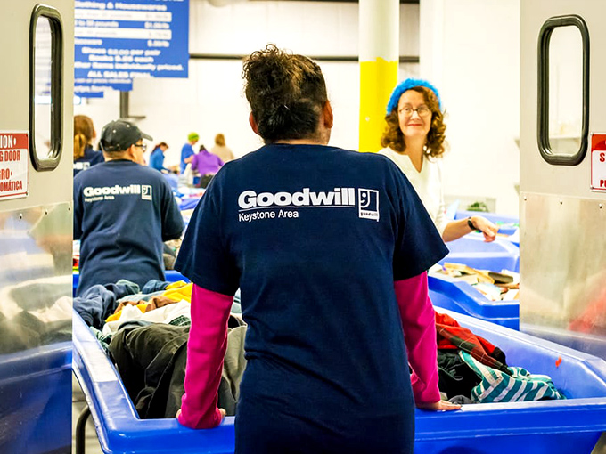 The blue-shirted staff, unsung heroes of the thrift ecosystem, refreshing bins with new possibilities. Their pink gloves are the mark of seasoned professionals.
