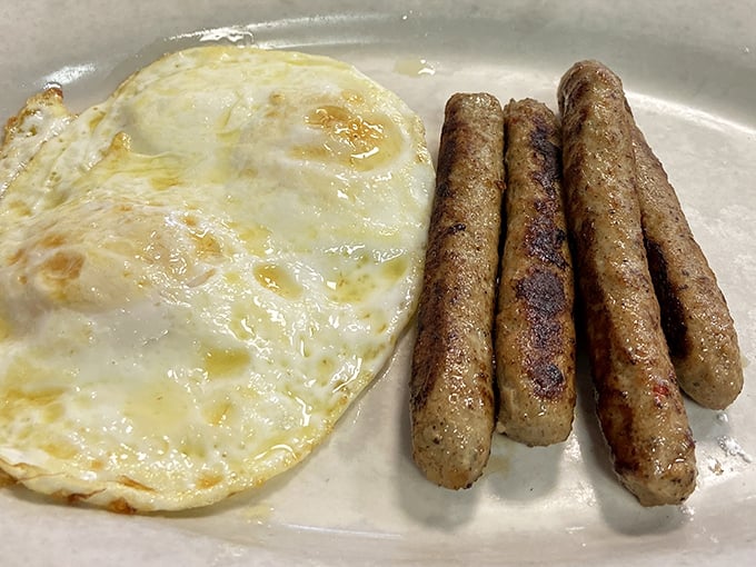 The perfect sunny-side up egg alongside sausage links that have achieved that ideal snap-when-bitten texture. Breakfast fundamentals executed flawlessly.