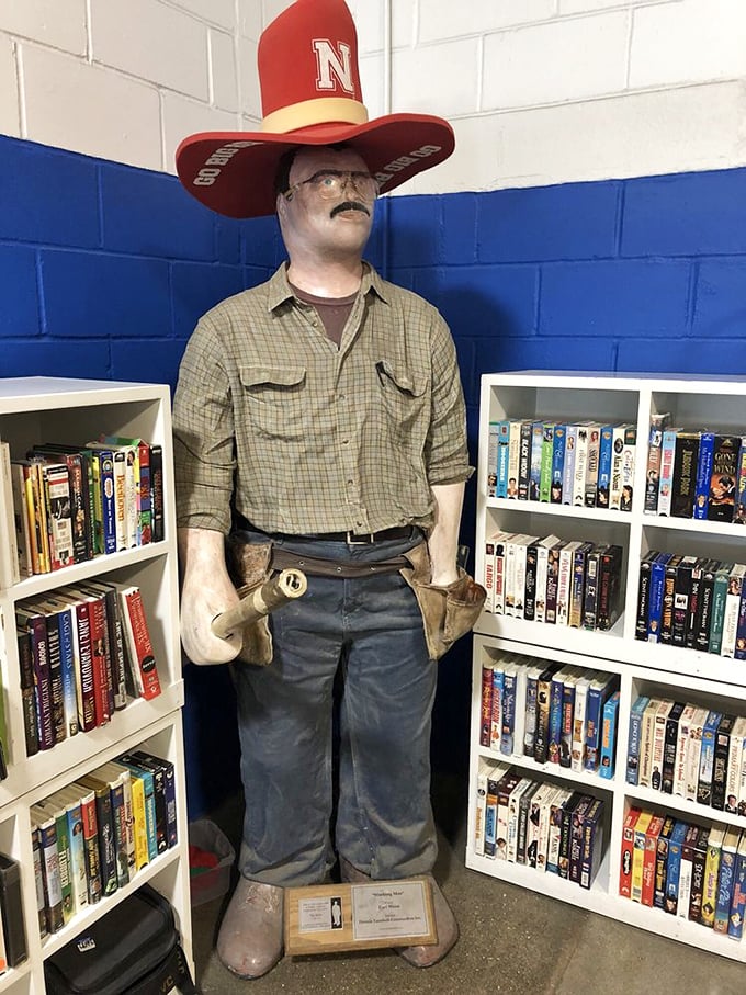 A Nebraska Cornhuskers superfan mannequin stands guard over the media section. VHS tapes and DVDs tell stories of entertainment evolution alongside forgotten bestsellers.