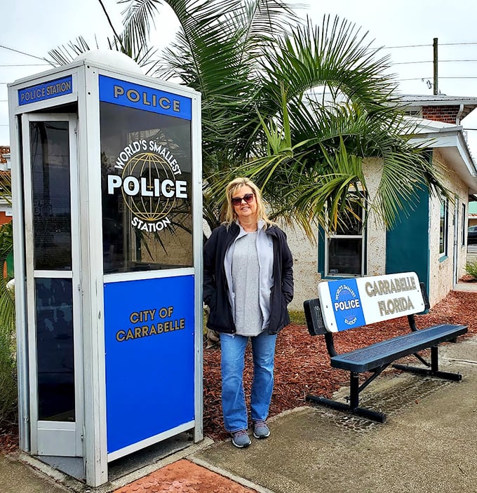 Size comparison is everything—this visitor demonstrates that the World's Smallest Police Station truly lives up to its name.