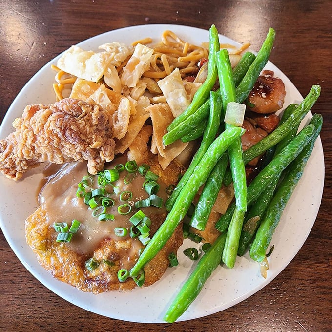 The art of buffet plate arrangement rivals Olympic tetris—crispy chicken, noodles, and vibrant green beans competing for precious real estate.
