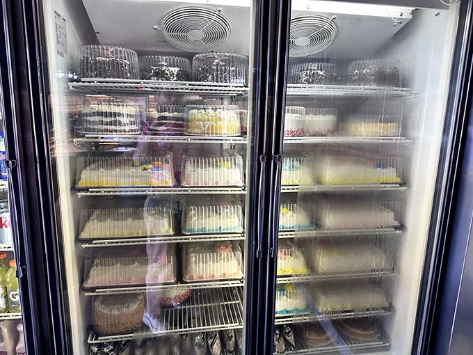 The refrigerated cake display—where birthdays, anniversaries, and "I'm sorry I forgot our anniversary" celebrations begin their journey to redemption.