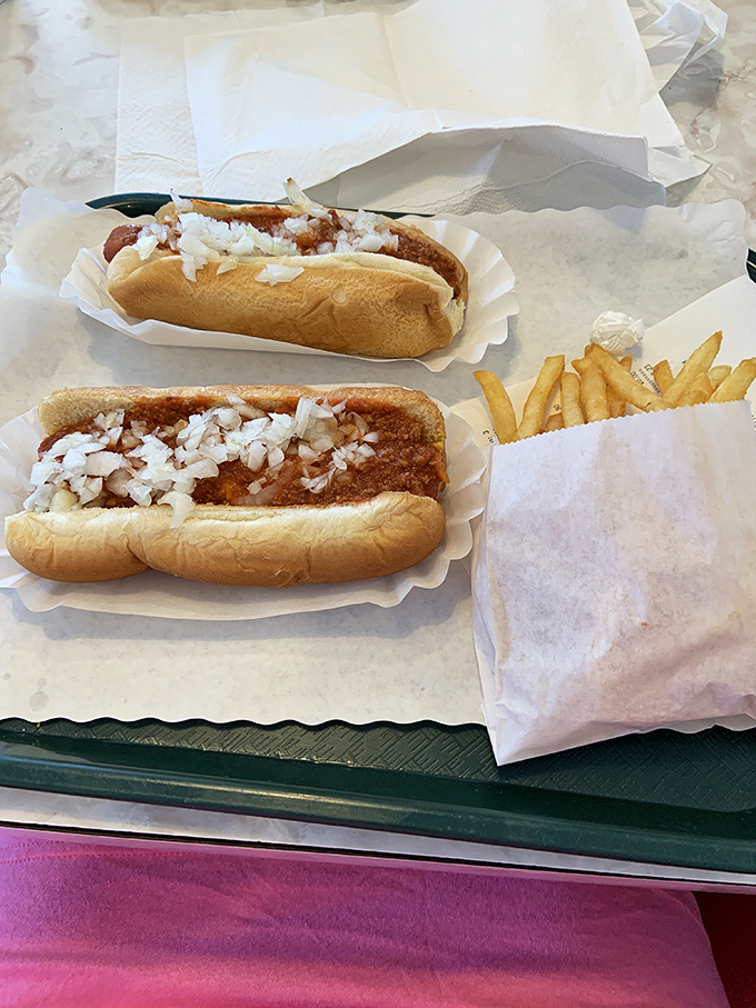 Chili dogs topped with diced onions—where messy meets magnificent in a handheld masterpiece that's worth every napkin you'll need.