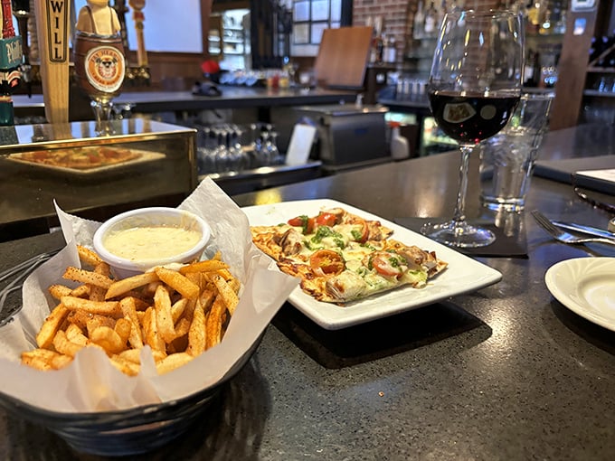 Bar dining done right—crispy fries, a flatbread that demands attention, and a glass of red that's saying "slow down, savor this moment."