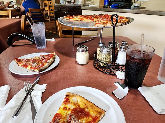 The classic pizza parlor experience lives on. That elevated pie stand, the table condiments, the soda in proper glasses—some traditions are worth preserving.