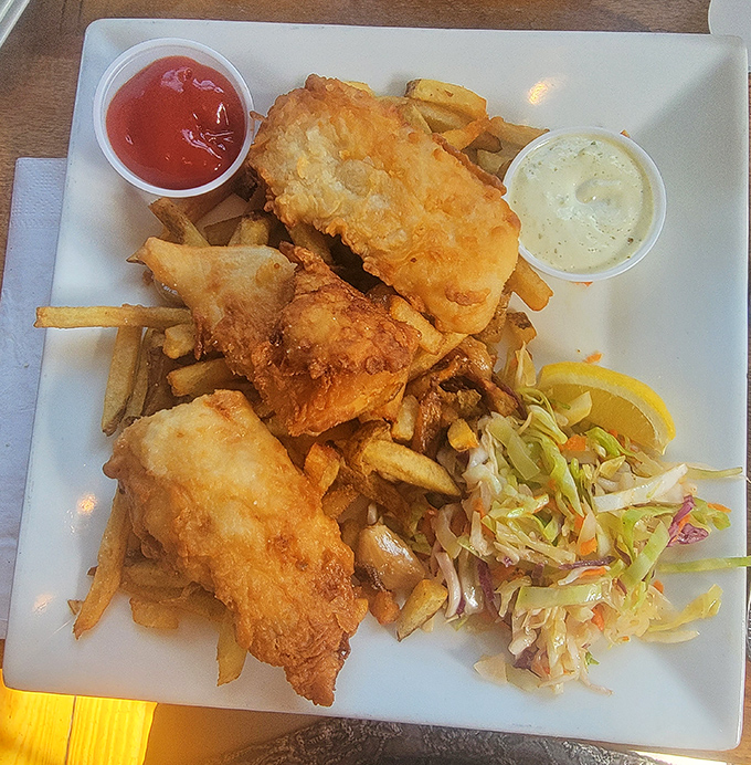 Fish and chips that would make New England proud—crispy, golden batter protecting flaky white fish, with fries and slaw playing perfect supporting roles.