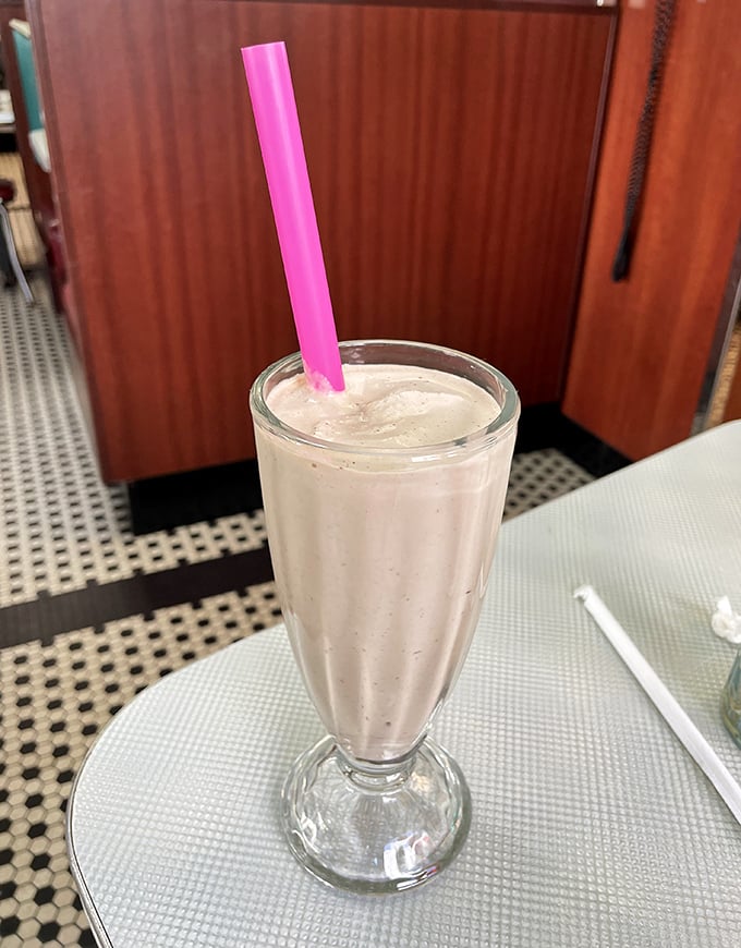 A milkshake so thick the straw stands at attention – this isn't just dessert, it's an engineering marvel with a pink straw crown.