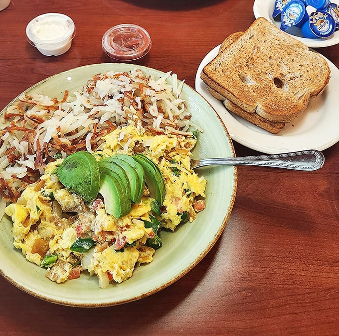 This isn't just breakfast, it's art – scrambled eggs nestled against crispy hash browns with avocado adding that California cameo.
