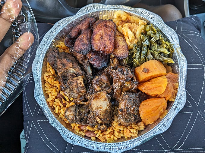 A mountain of jerk chicken atop rice with collard greens and candied yams – proof that the best things in life come in takeout containers.