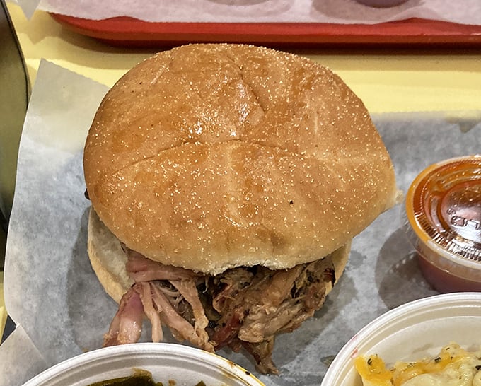 A pulled pork sandwich so generously stuffed, it requires both hands and possibly a backup napkin supply.