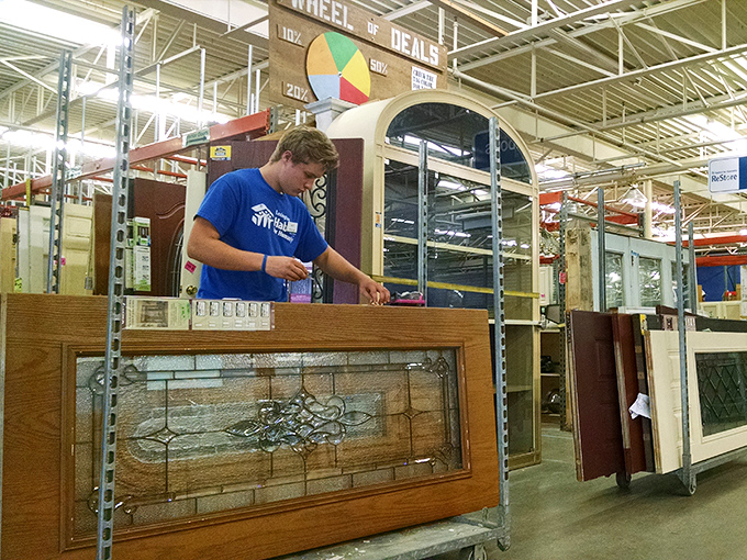 A staff member carefully examines a stained glass window, part of the meticulous quality control that ensures every treasure is ready for its new home.