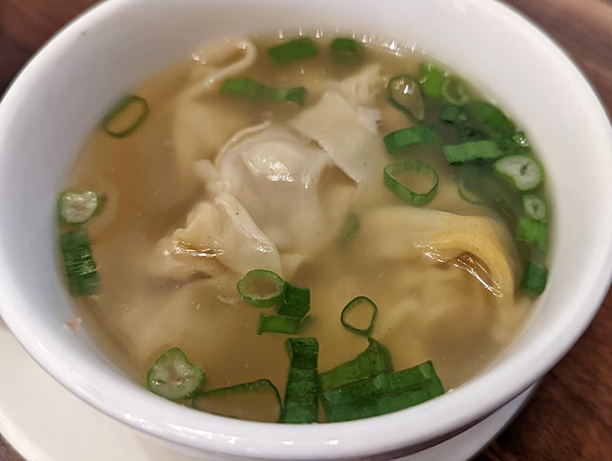 The famous wonton noodle soup in all its glory—dumplings floating like tasty little life rafts in a broth that deserves its own spa day.