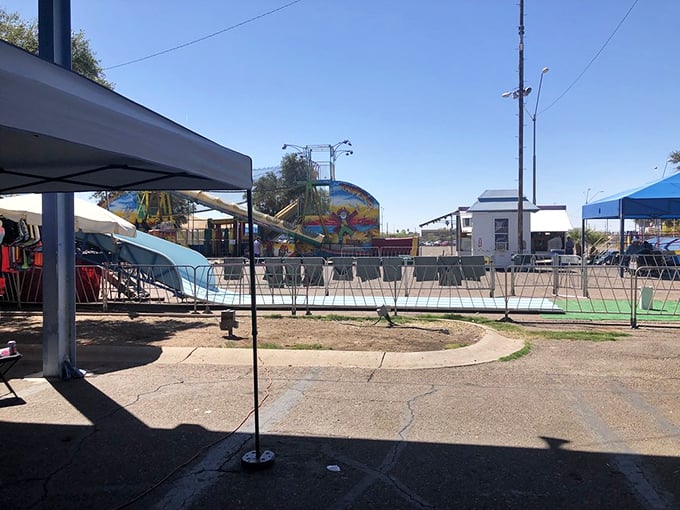 Carnival meets commerce! Beyond Greyhound's blue fence, colorful rides spin under perfect Arizona skies—because nothing works up an appetite for bargain hunting like a whirl on the teacups.