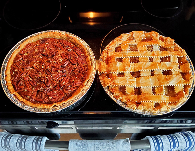 Pecan pie and apple pie sitting side by side like old friends – the sweet, sticky Southern classic alongside America's favorite, both begging for a scoop of vanilla.