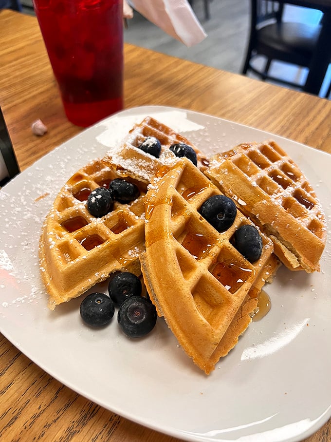Belgian waffles with fresh blueberries and a dusting of powdered sugar – breakfast that doubles as dessert without a hint of guilt.