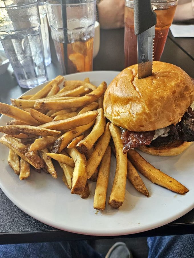 Not just a burger, but a towering achievement in sandwich architecture that requires both hands, several napkins, and absolutely zero shame.