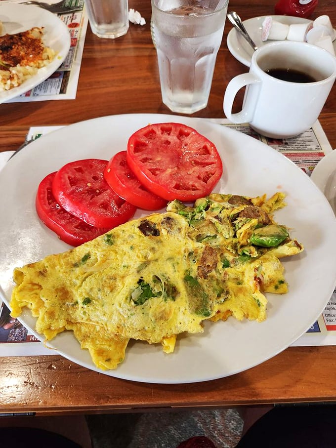 Breakfast artistry at work—a perfectly executed omelet with vibrant tomato slices that could make a summer garden jealous. Morning fuel that respects your taste buds.