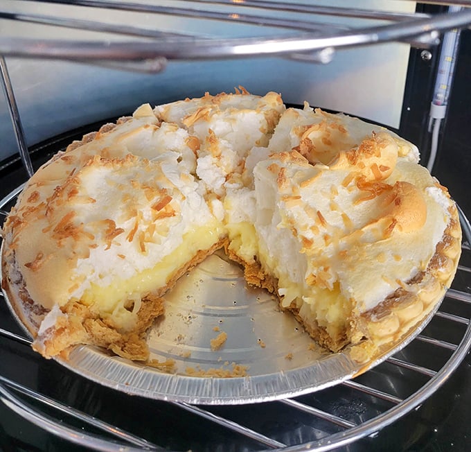 Coconut meringue pie with a mile-high crown of toasted fluff—the kind of dessert that makes you consider ordering a second slice before finishing the first.