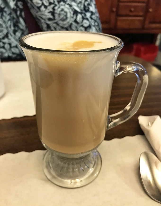 A proper latte in a glass mug because even your coffee deserves to feel fancy at this Danish-American breakfast paradise.