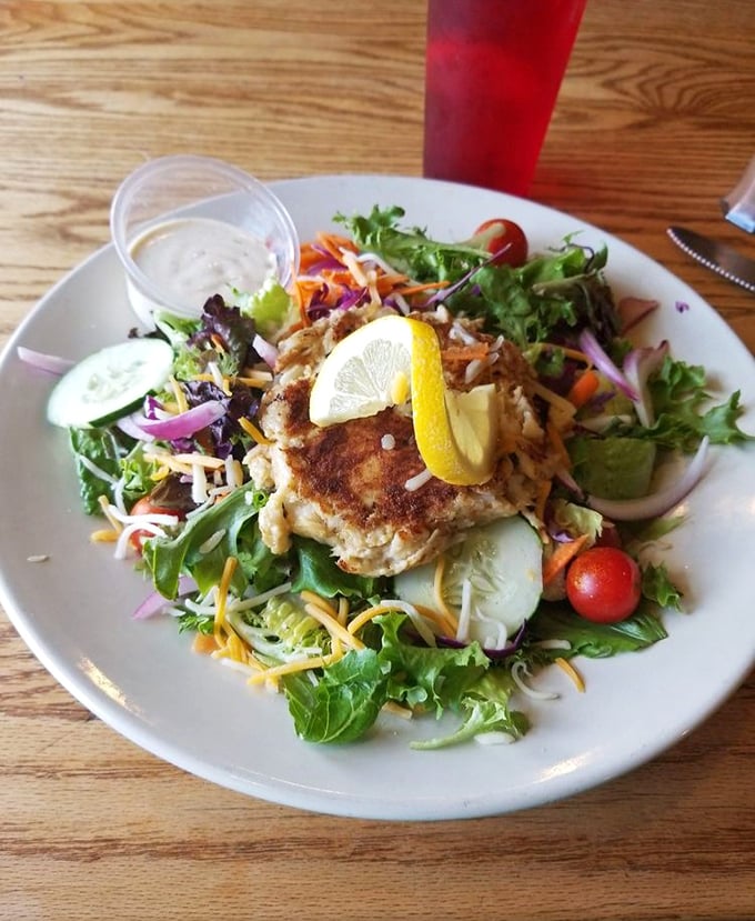 This isn't just any crab cake salad – it's a masterclass in balance, with a golden-brown patty perched atop a garden of fresh vegetables.