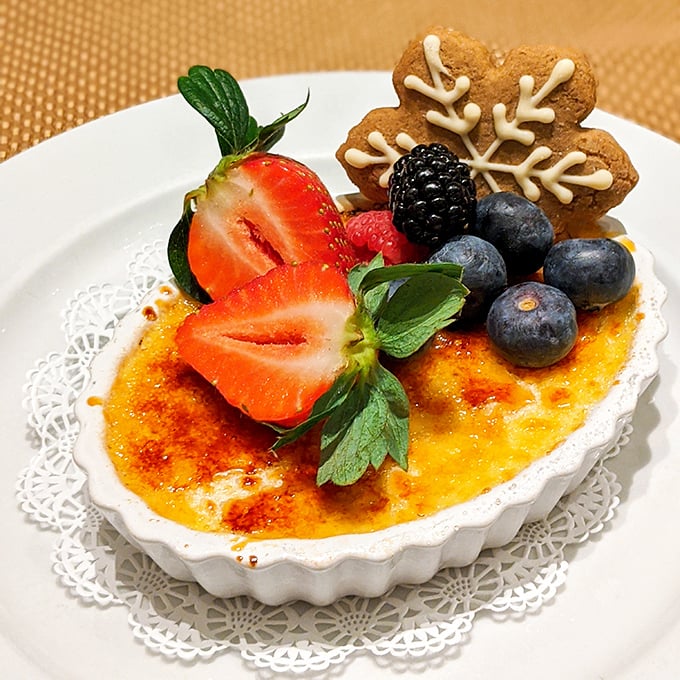 Crème brûlée with a perfectly torched sugar crust, crowned with fresh berries and a snowflake cookie—winter's most elegant dessert, regardless of the season.